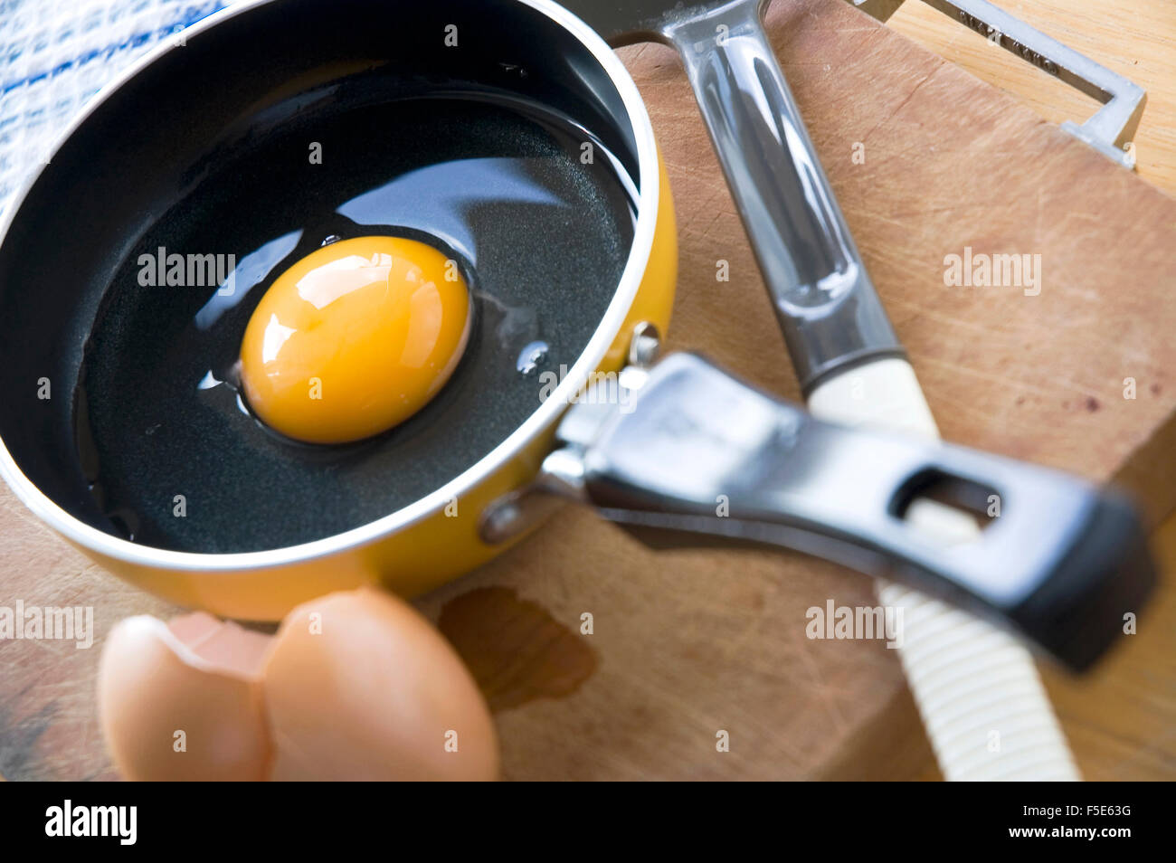 raw egg in yellow pan ready to cook Stock Photo - Alamy