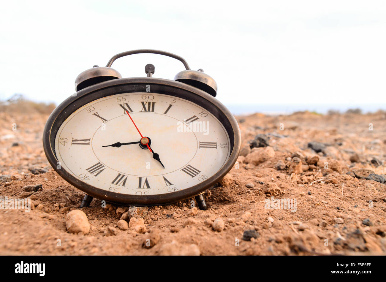 Classic Analog Clock In The Sand Stock Photo - Alamy