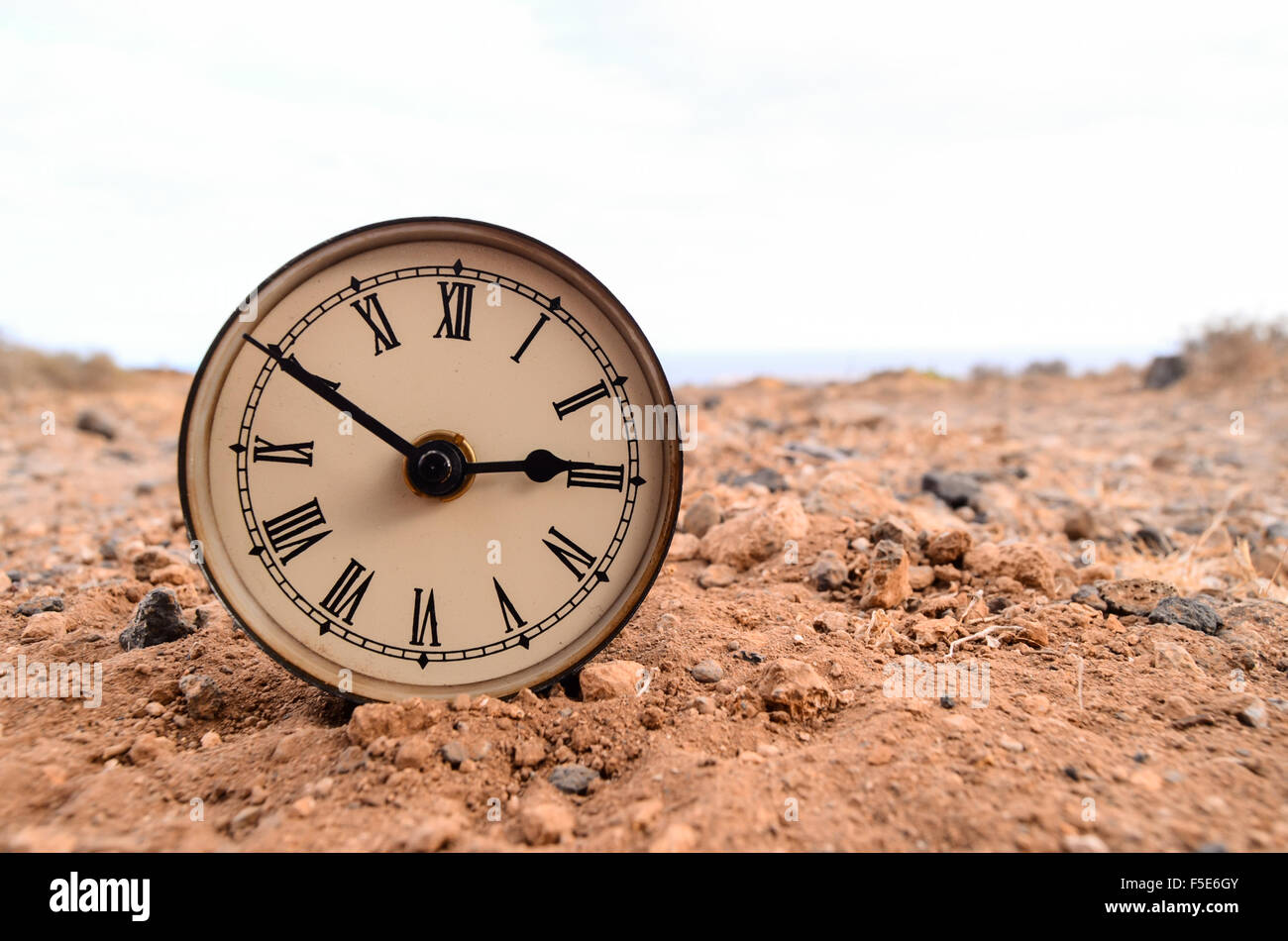 Classic Analog Clock In The Sand Stock Photo - Alamy