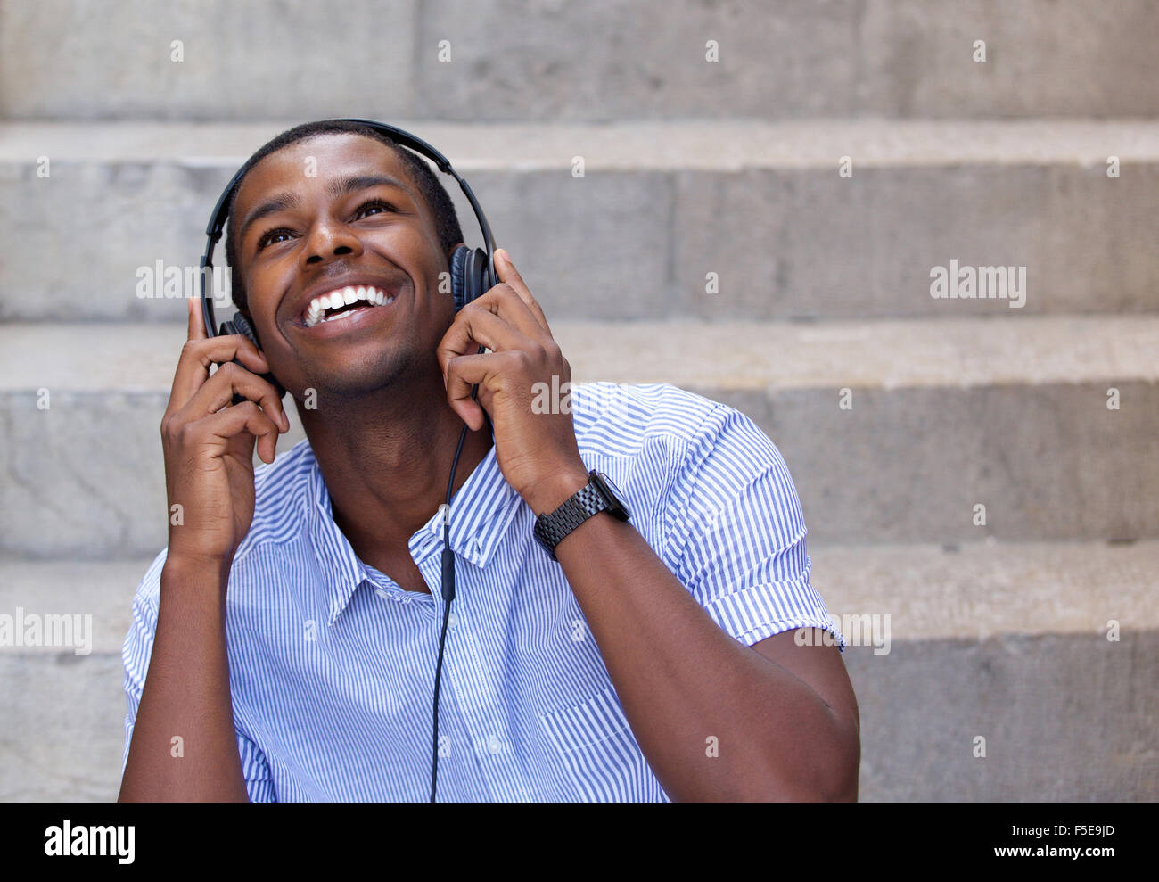 Close up portrait of a smiling young man listening to music on ...
