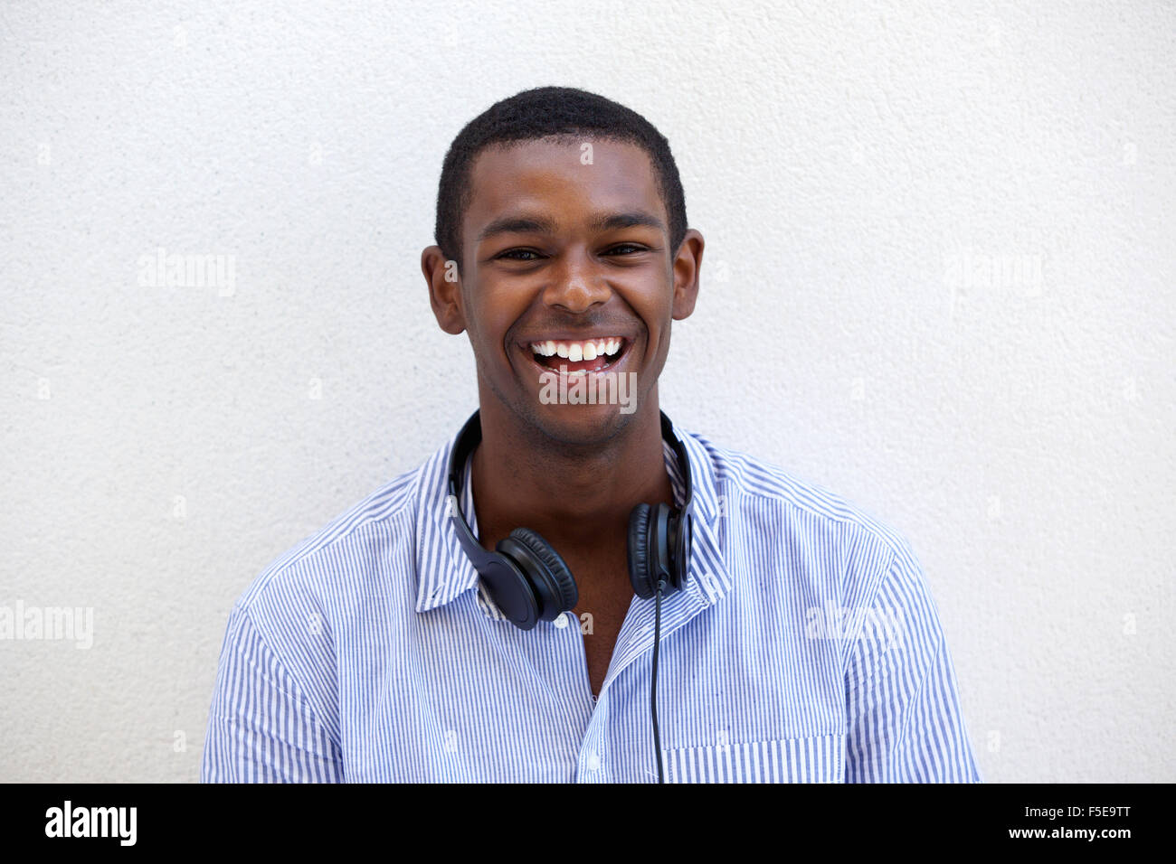Close up portrait of a happy young black man smiling with headphones on ...