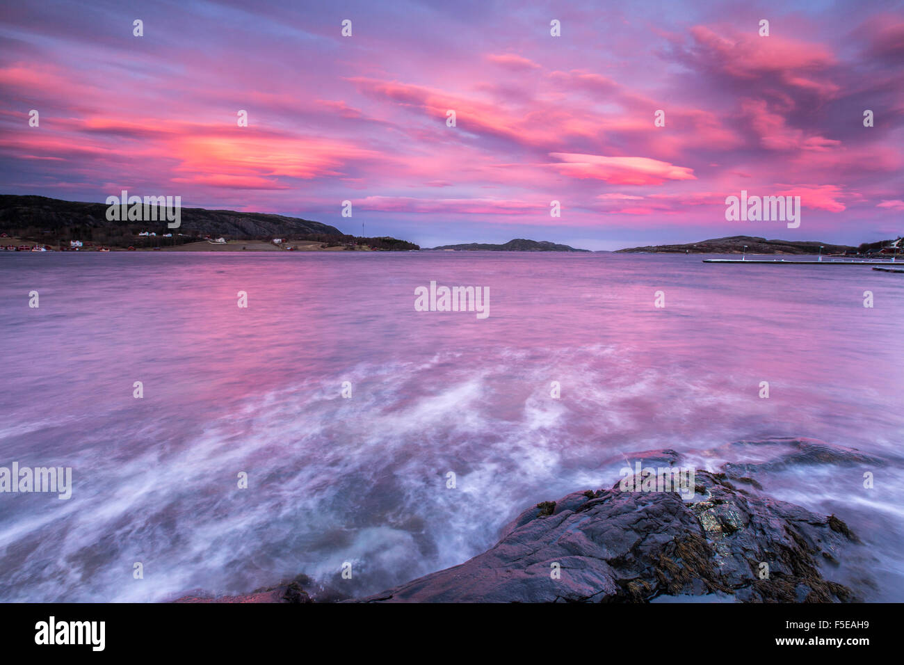 Pink sky at sunrise reflected in the cold waters, Flatanger, Trondelag ...