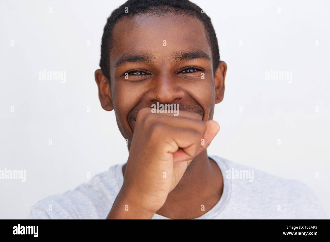 Close up portrait of a young african american man laughing with hand ...