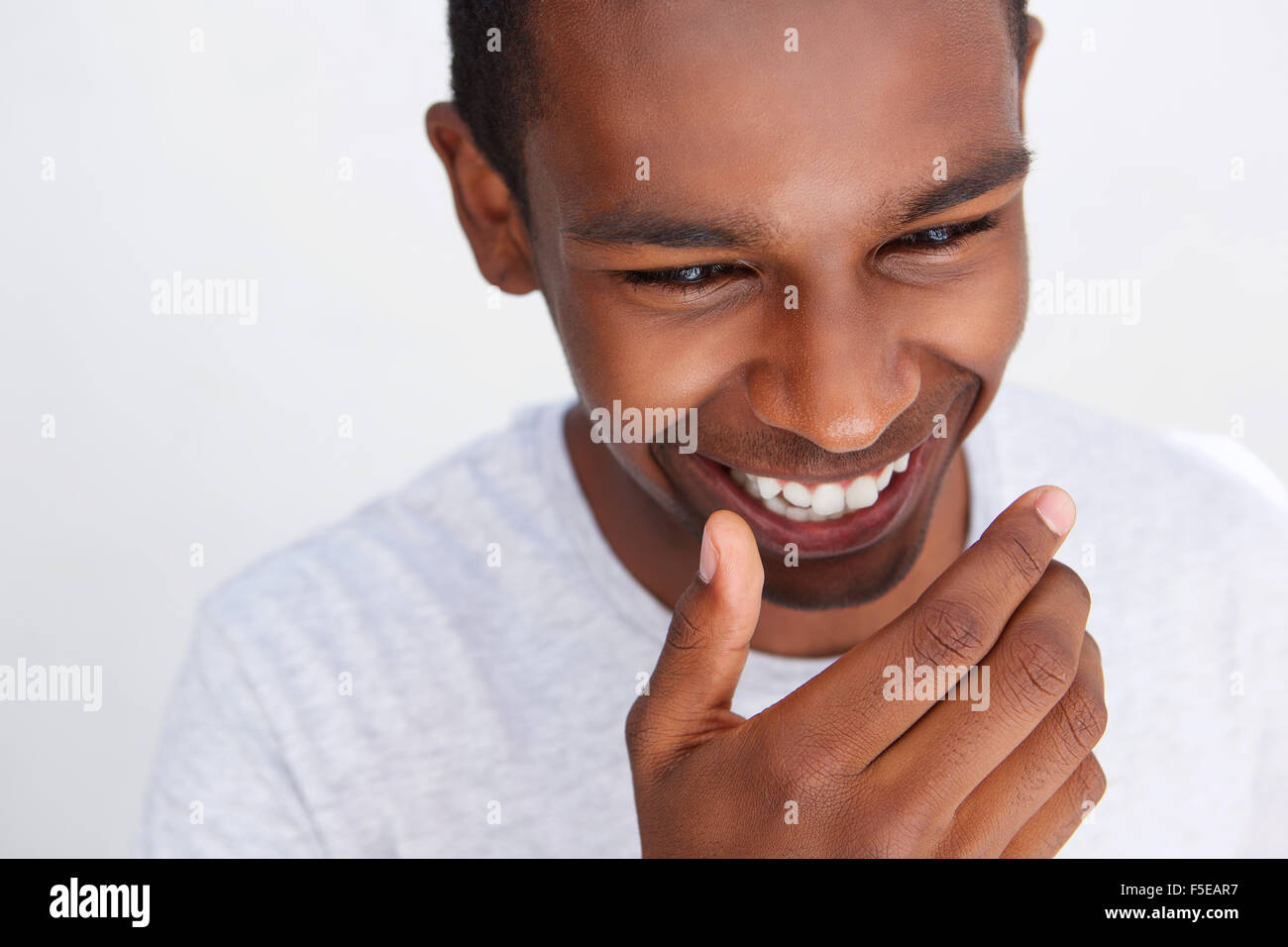 Close up portrait of a young guy laughing with hand covering mouth ...