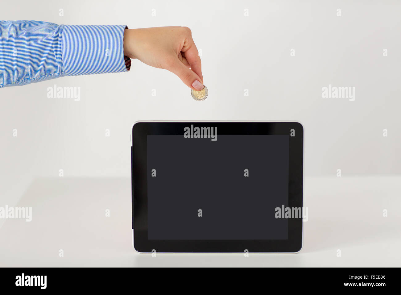 close up of hand putting coin into tablet pc Stock Photo - Alamy