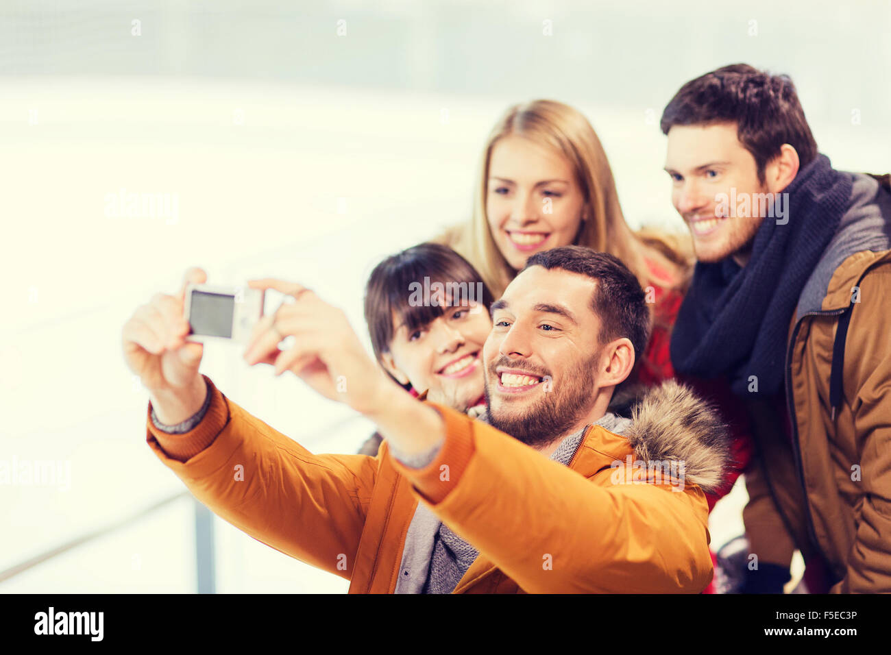 happy friends with camera on skating rink Stock Photo - Alamy