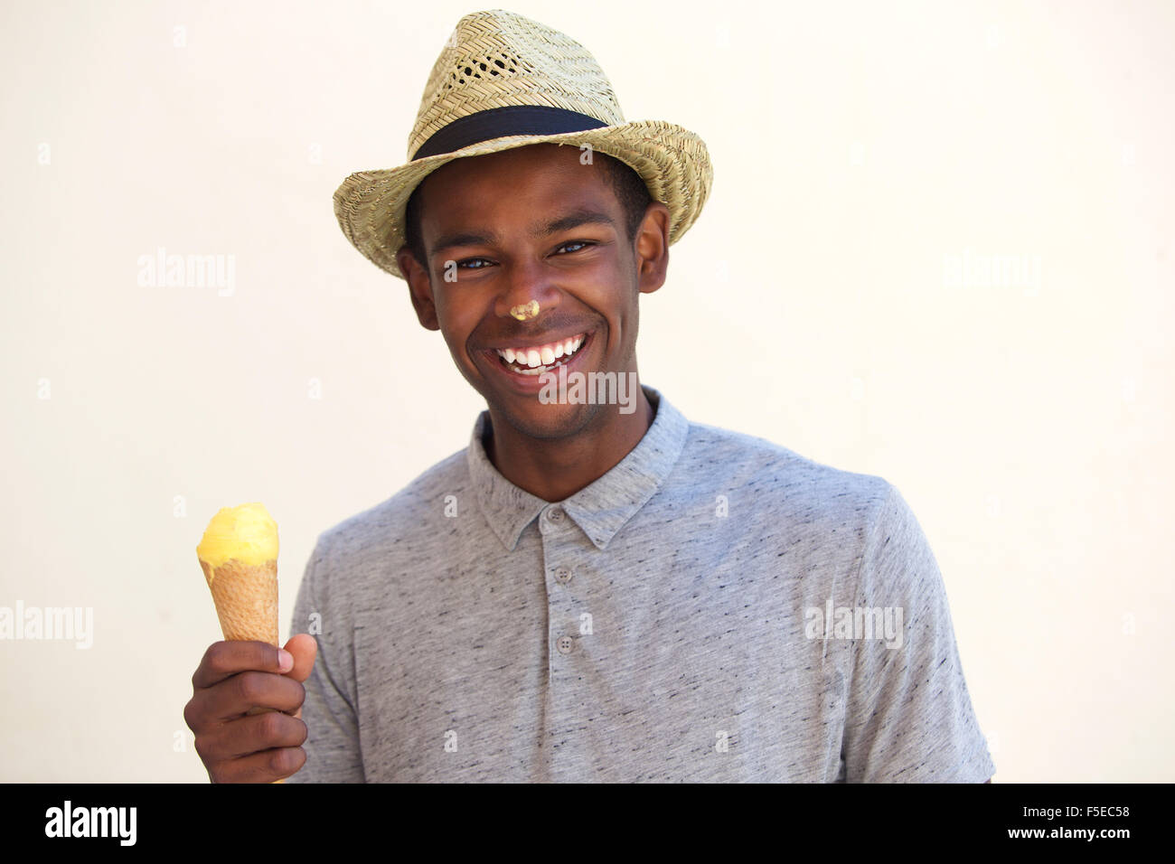 Close up portrait of a young man laughing with ice cream on his nose ...