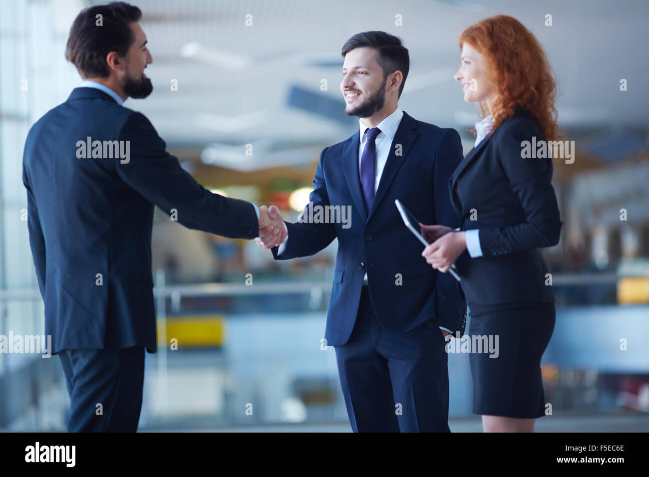 Businessmen handshaking with their colleague near by Stock Photo - Alamy