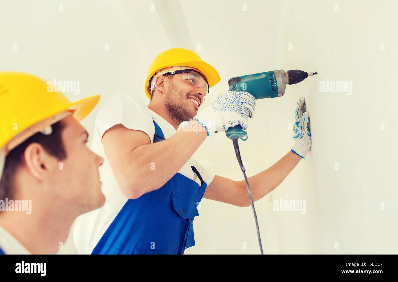 group of smiling builders with drill indoors Stock Photo - Alamy