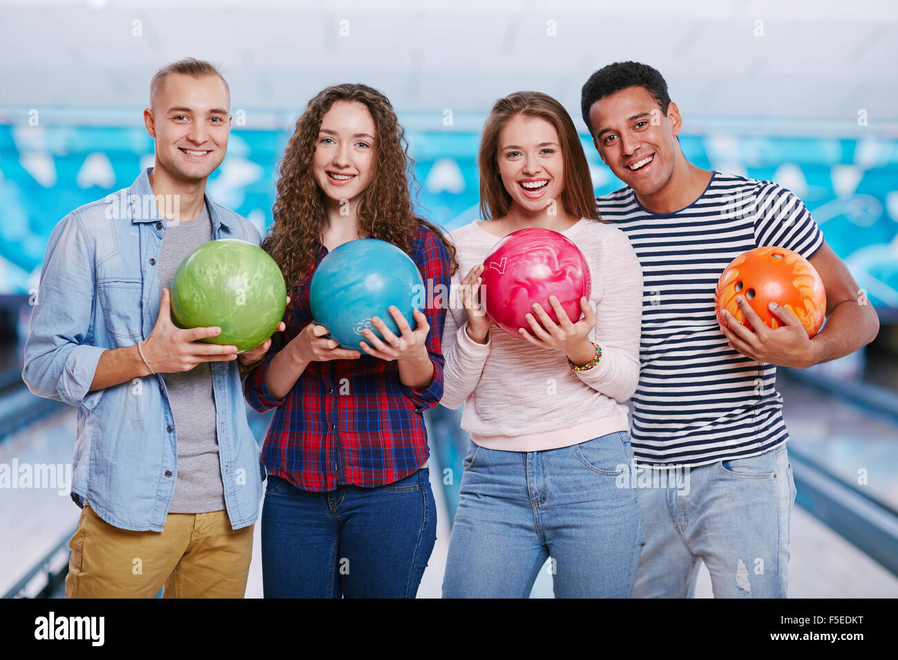 Cheerful friends with bowling balls looking at camera Stock Photo - Alamy