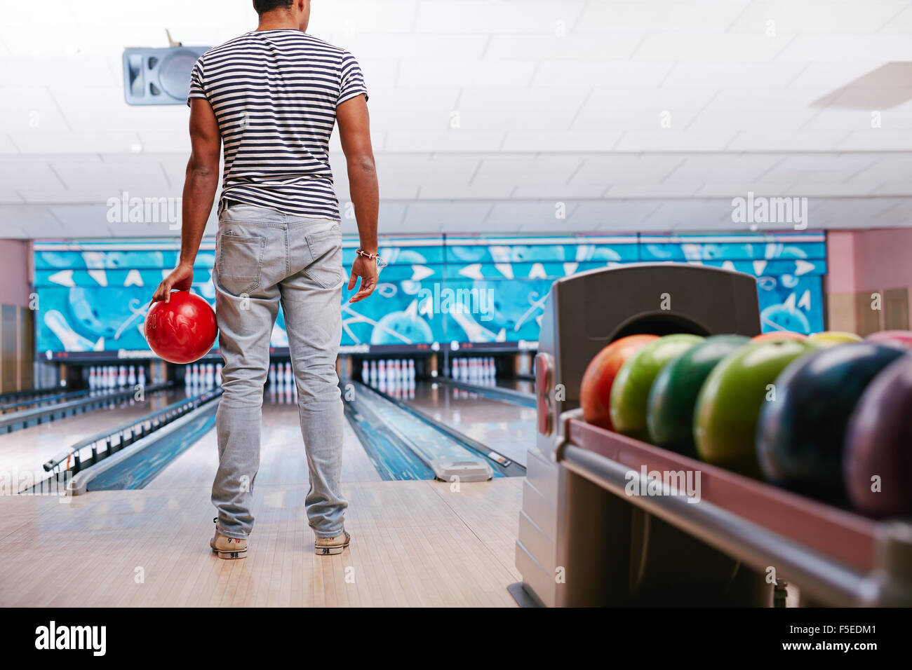 Young guy in casualwear playing bowling Stock Photo - Alamy