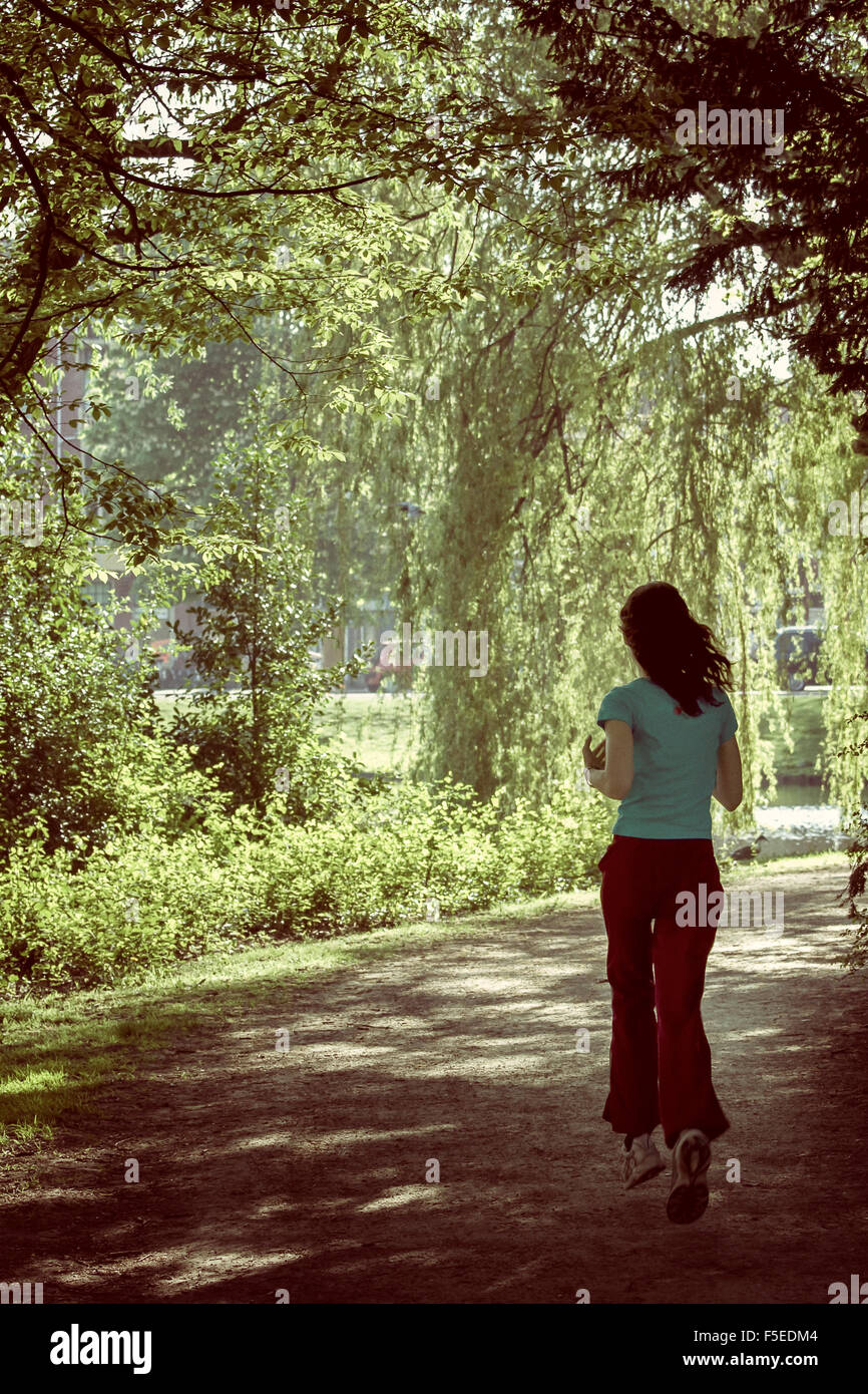 Slim girl running in park under sunlit trees Stock Photo - Alamy