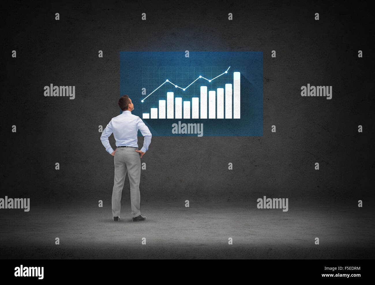 businessman looking at chart over concrete room Stock Photo - Alamy