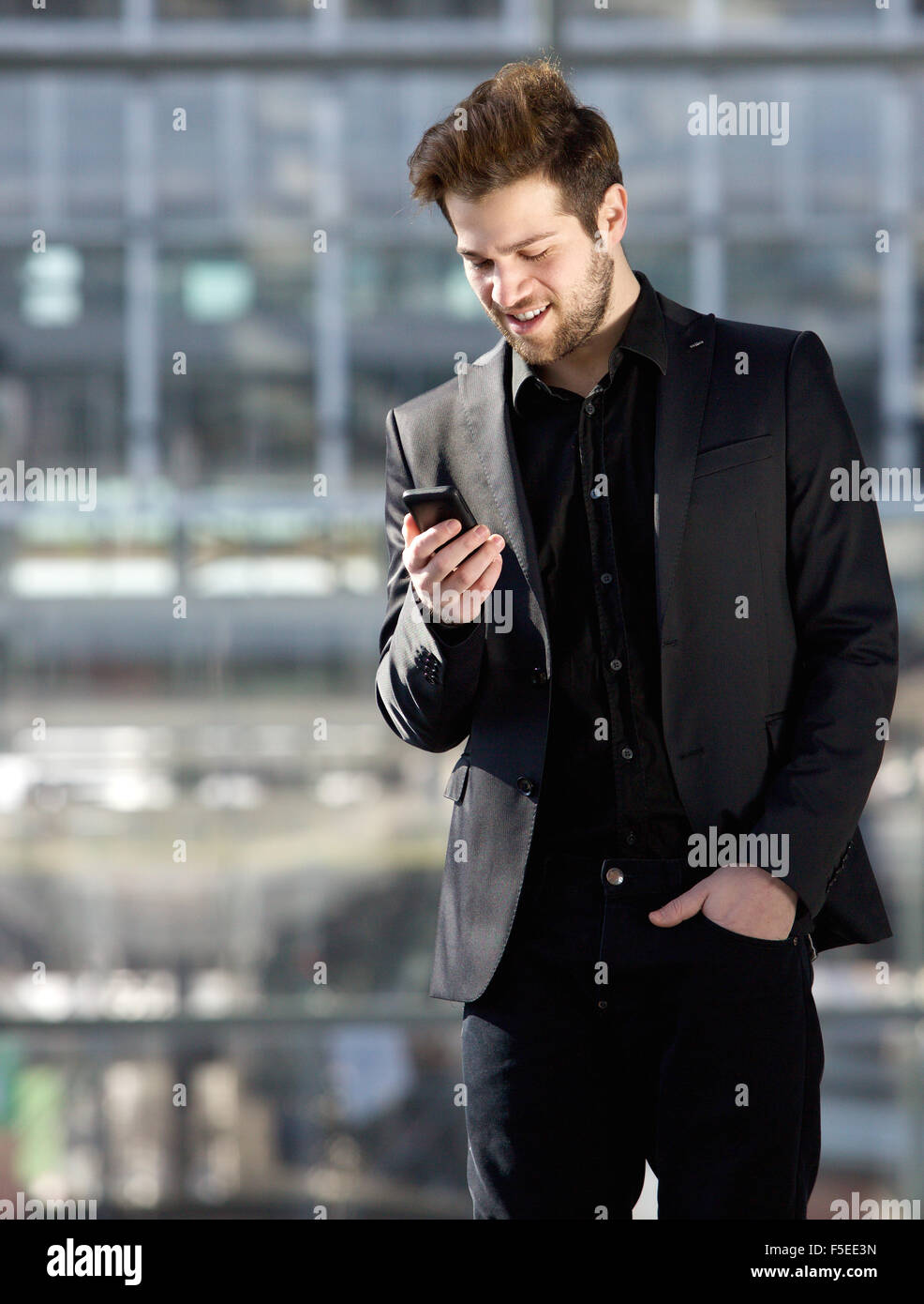 Portrait of a handsome young man looking at mobile phone text message ...
