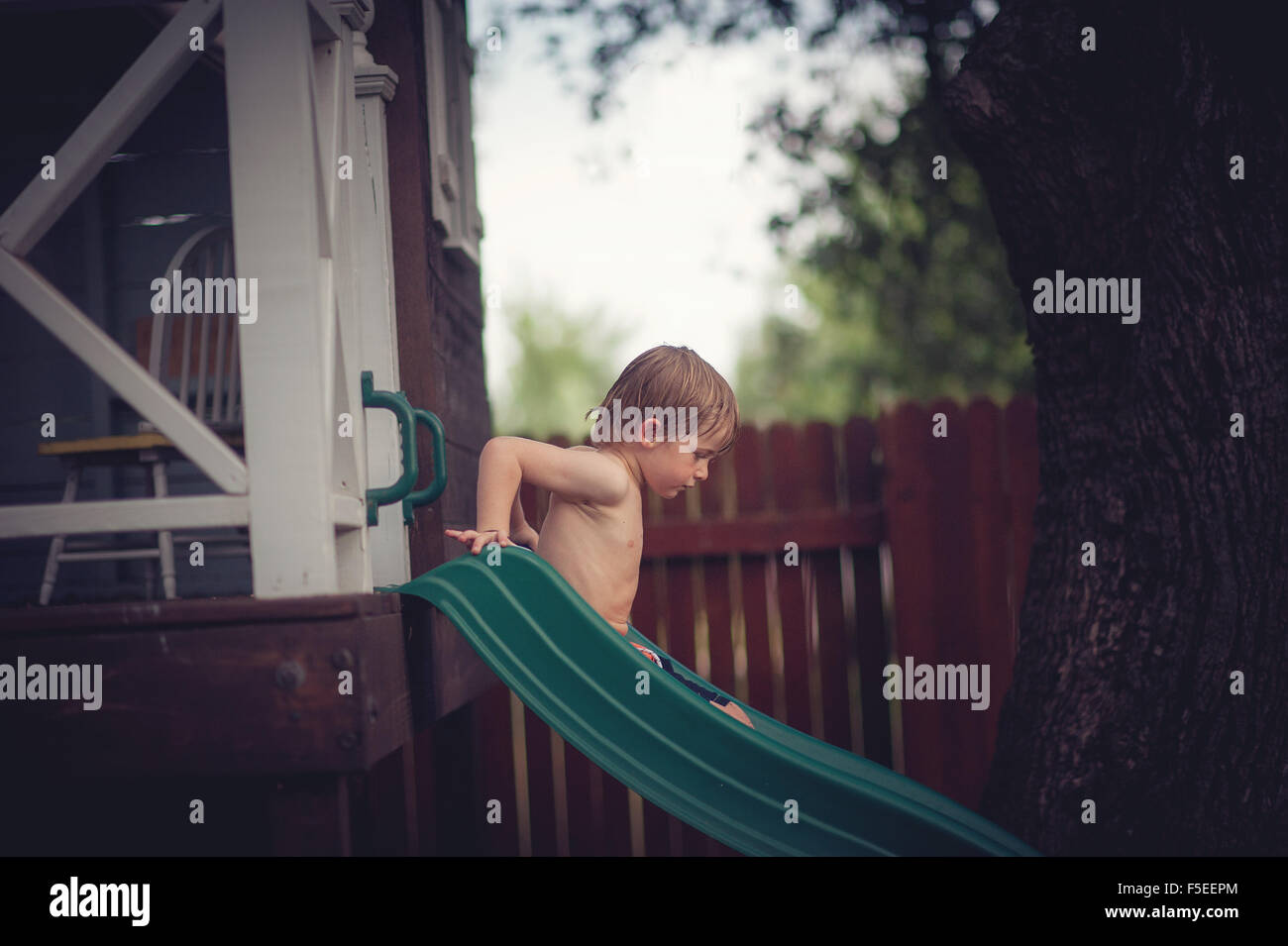 Boy on slide in backyard Stock Photo - Alamy