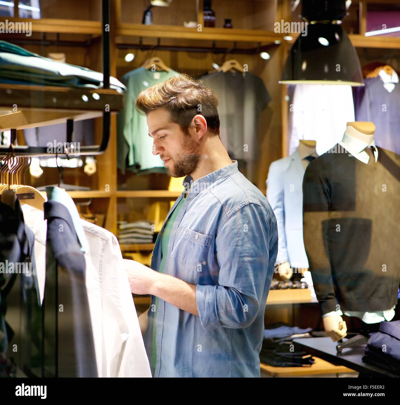 Portrait of a handsome young man shopping for clothes at shop Stock ...