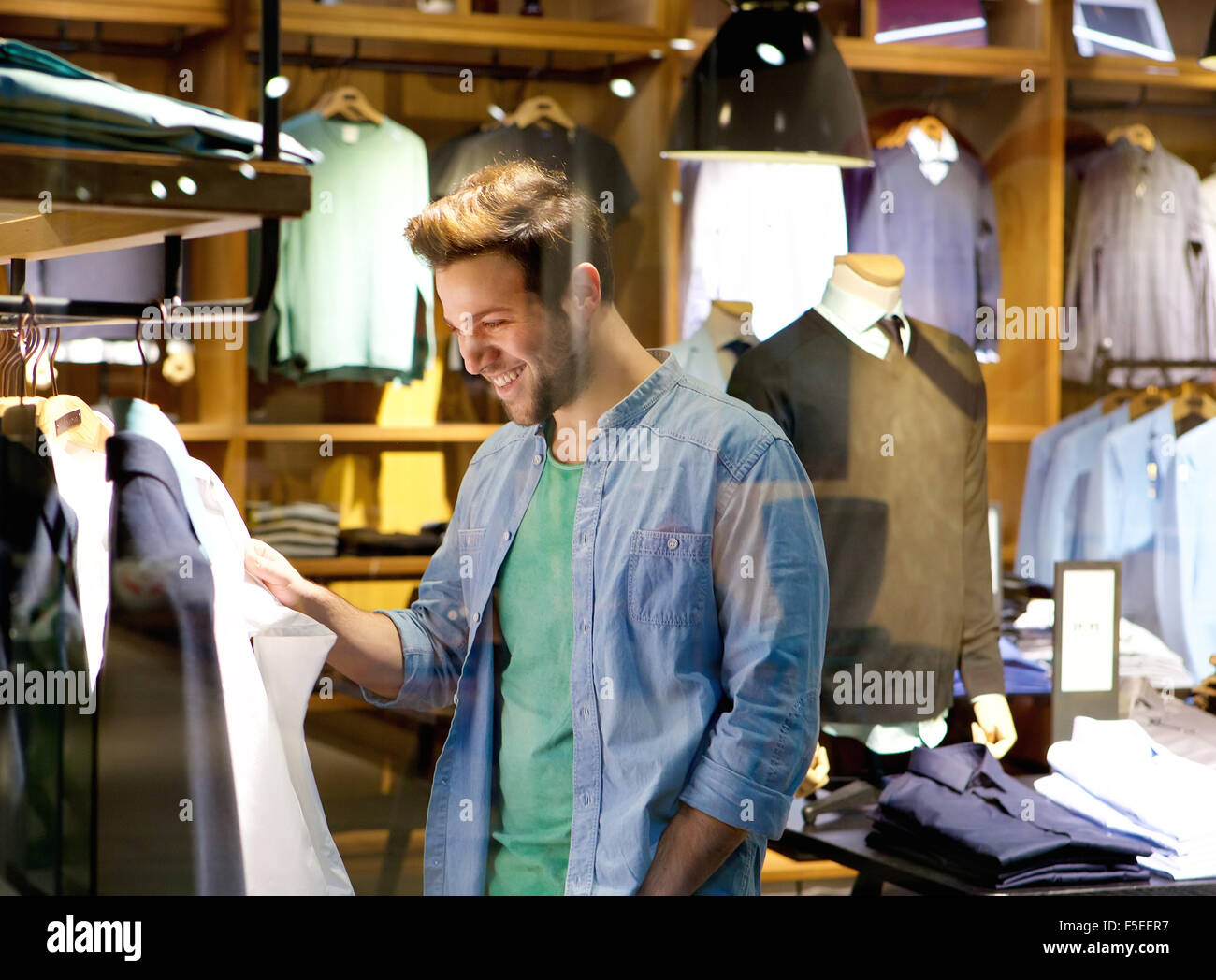 Portrait of a smiling man shopping for clothes at clothing store Stock ...