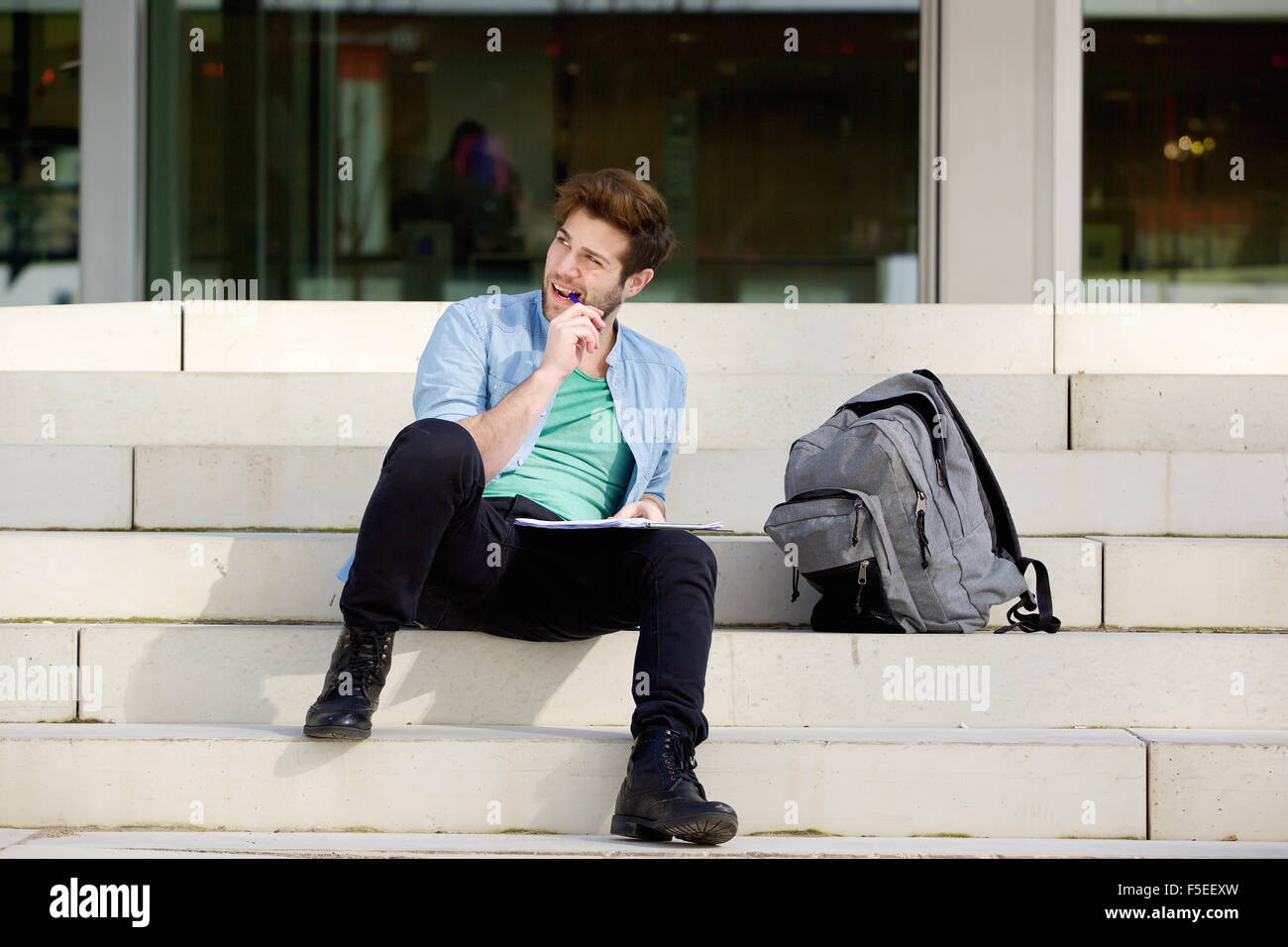 Portrait of a male student sitting outside on campus thinking Stock ...