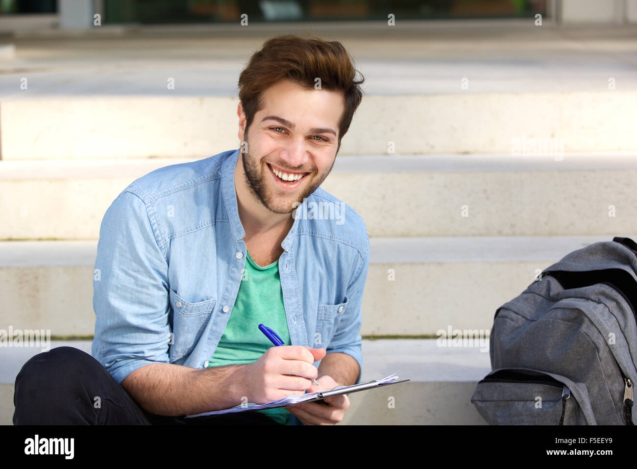 Portrait of a happy college student writing on notepad outside Stock ...