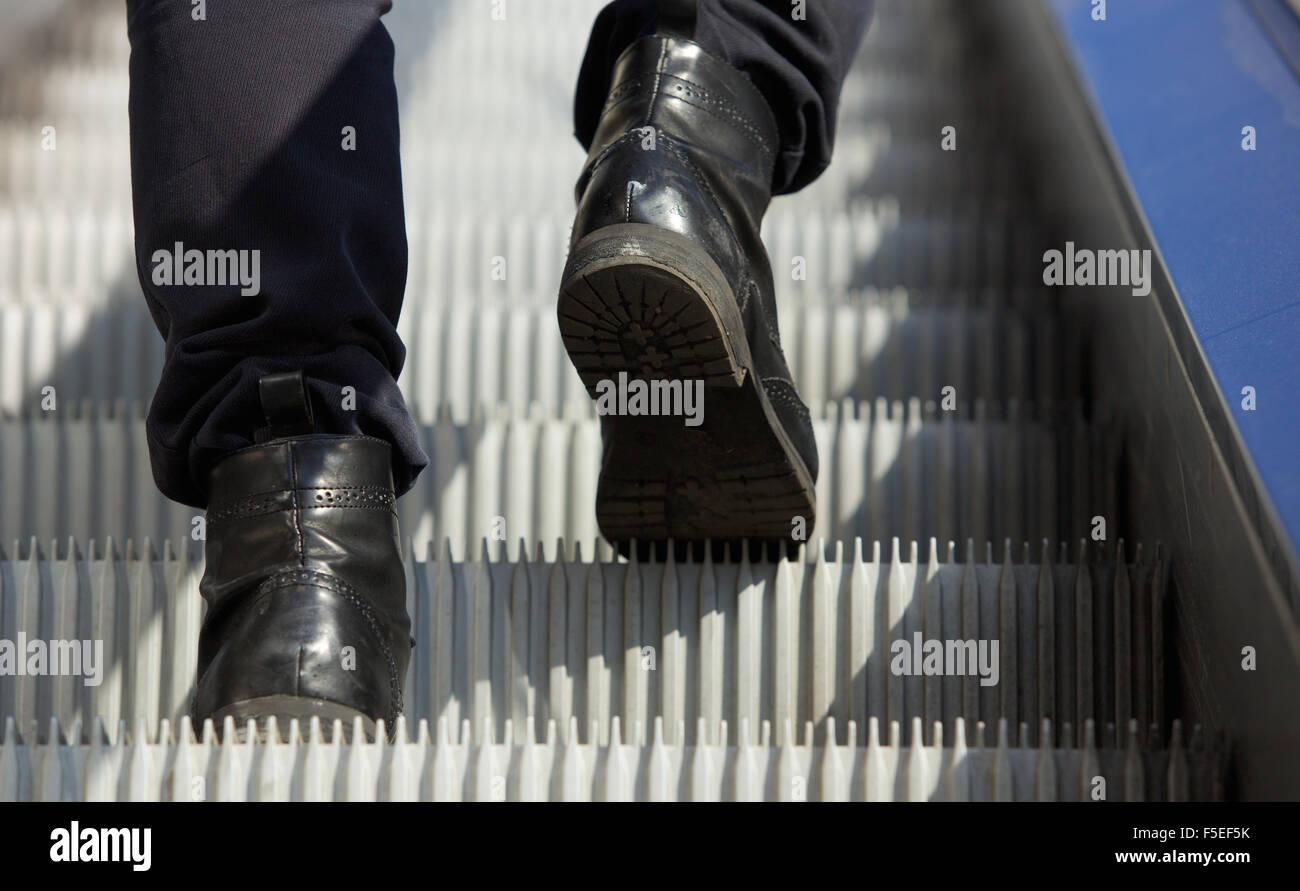 Low angle male feet walking in boots up escalator Stock Photo - Alamy