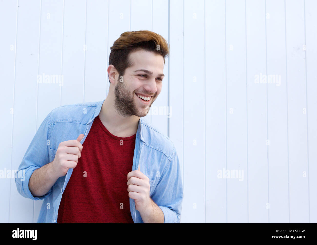Portrait of a cool male fashion model smiling against white background ...