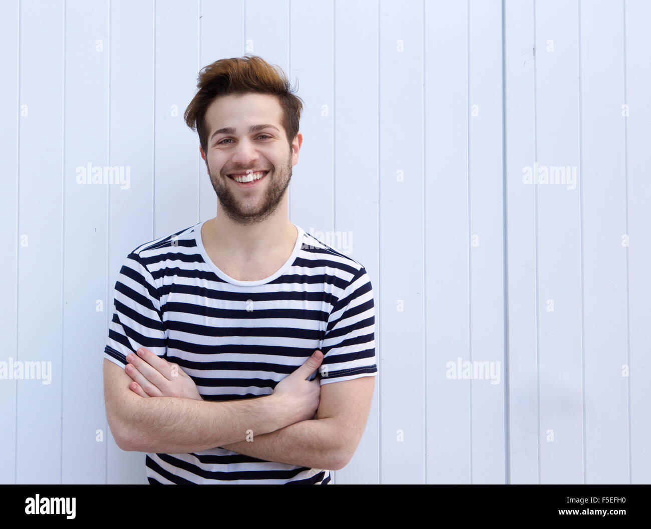 Portrait of a cute guy smiling with arms crossed on white background ...
