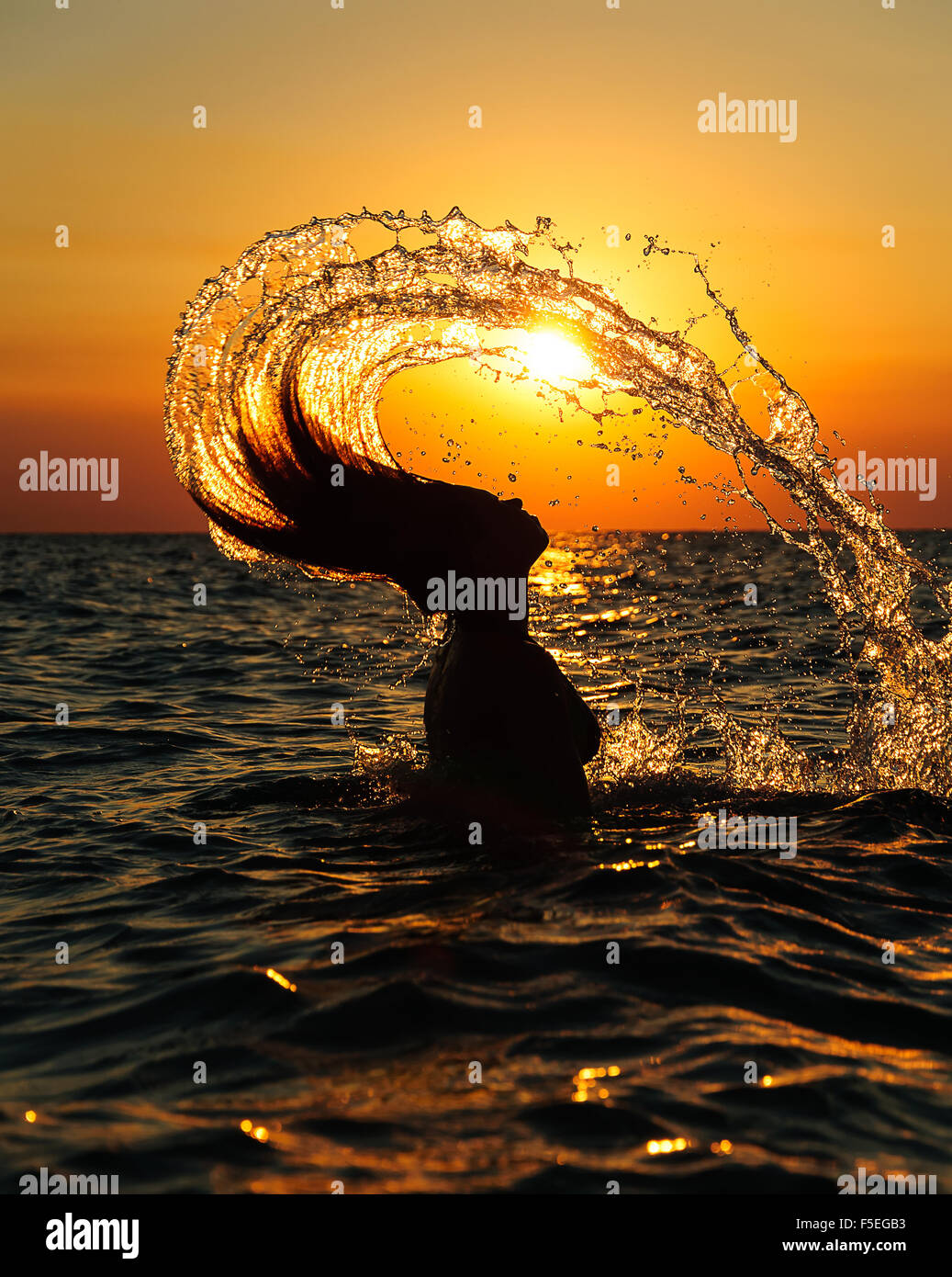 Silhouette of woman in sea throwing her head back Stock Photo - Alamy
