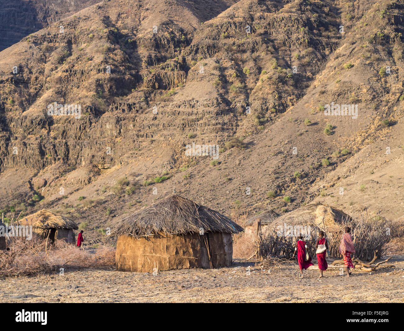 Three kids walking in a Maasai village in front of the Ol Doinyo Lengai ...