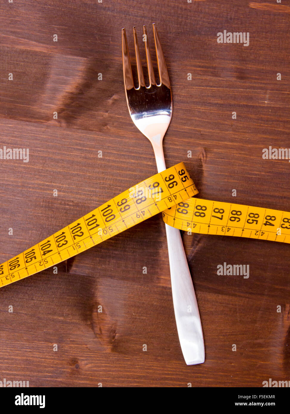 Fork with tape measure on wooden table Stock Photo - Alamy