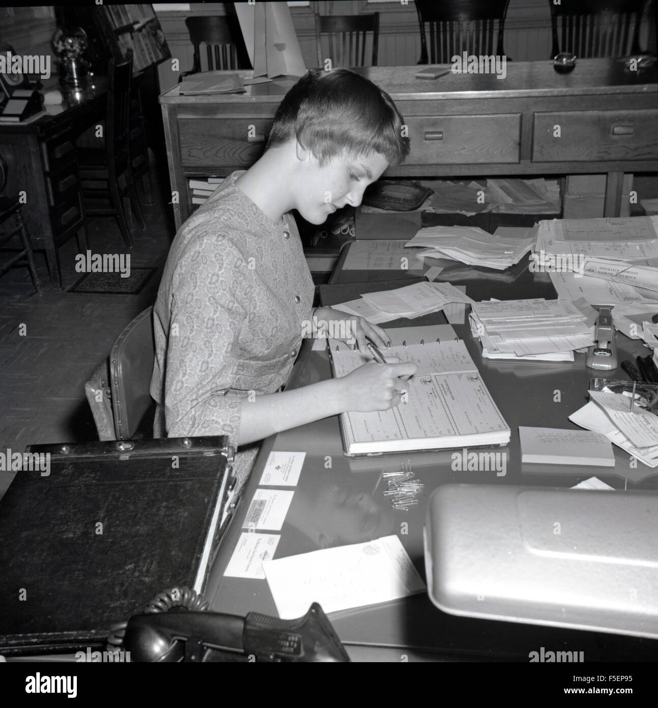 1950s historical, young woman working at a desk, writing notes in a ...