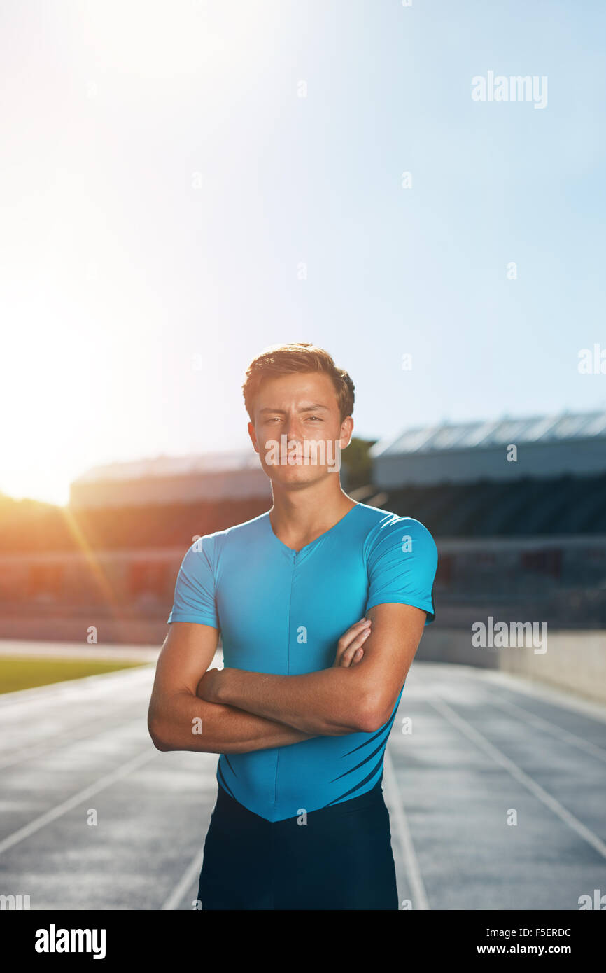Professional male track athlete standing with his arms crossed looking ...
