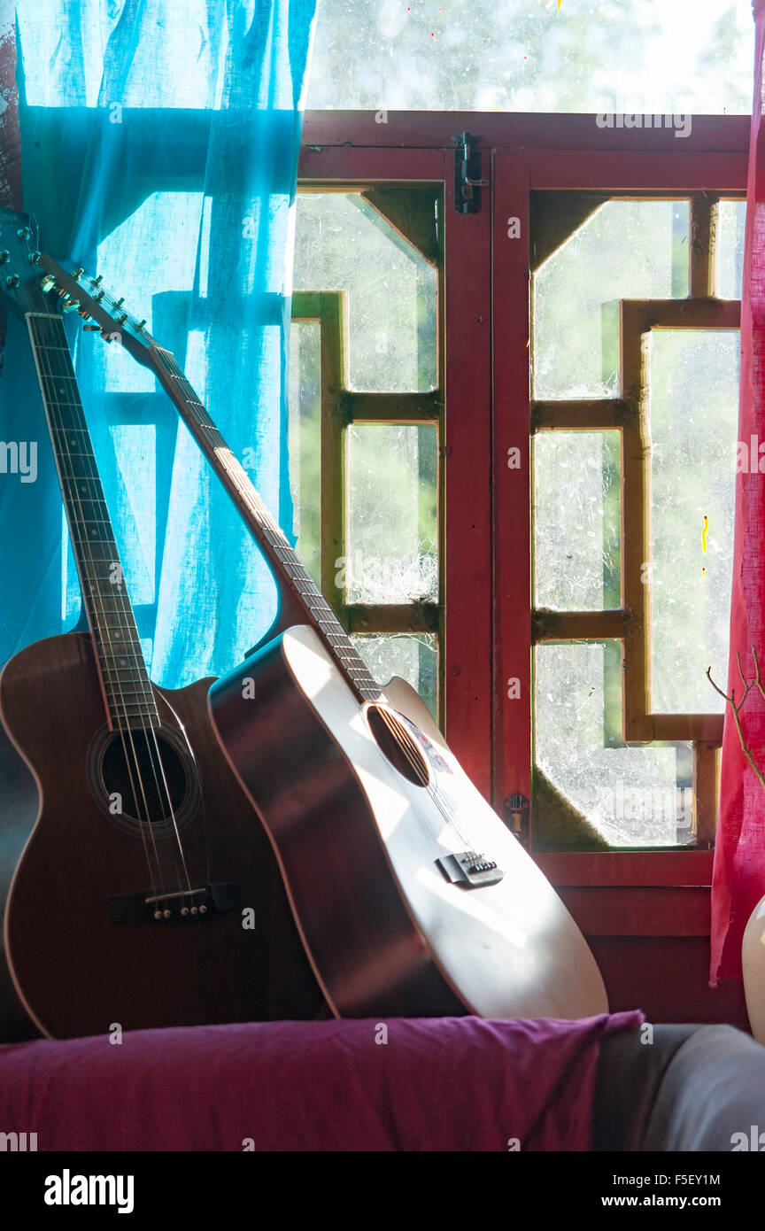 Guitar put next to window with sun Stock Photo - Alamy