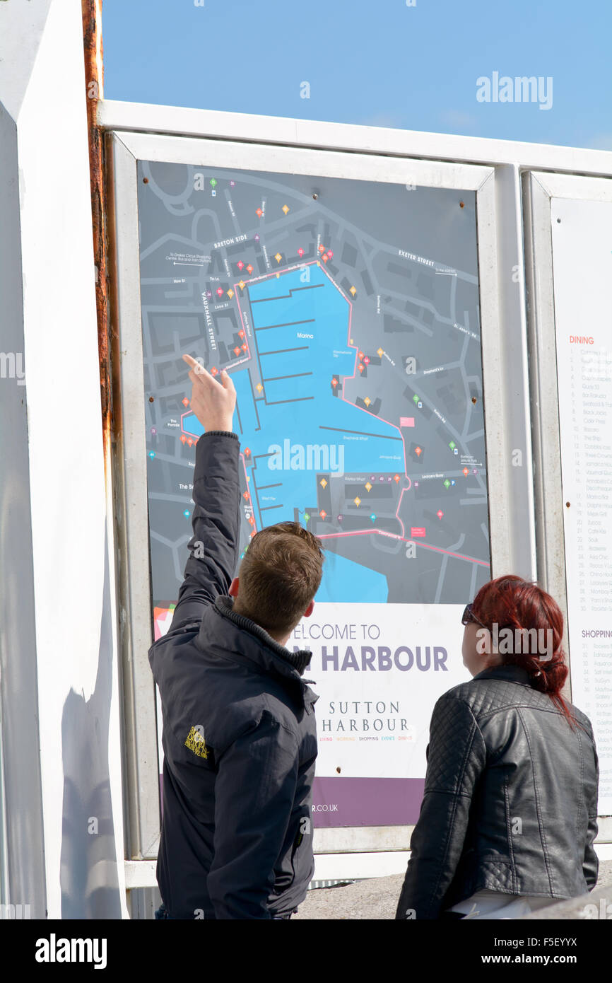 Man pointing to places on Sutton Harbour information map as girlfriend ...