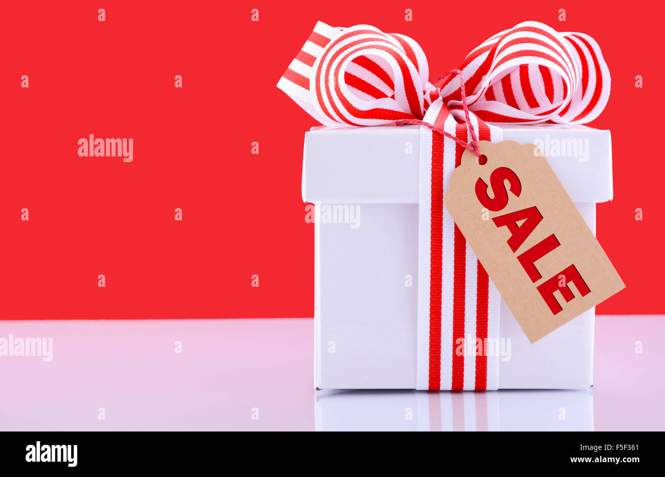 red and white sales promotion gift box on white reflective table ...