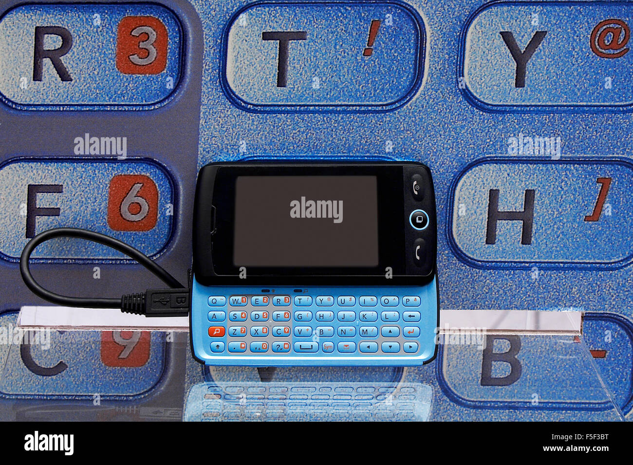 Mobile phone and palmtop against keyboard image with letters and ...