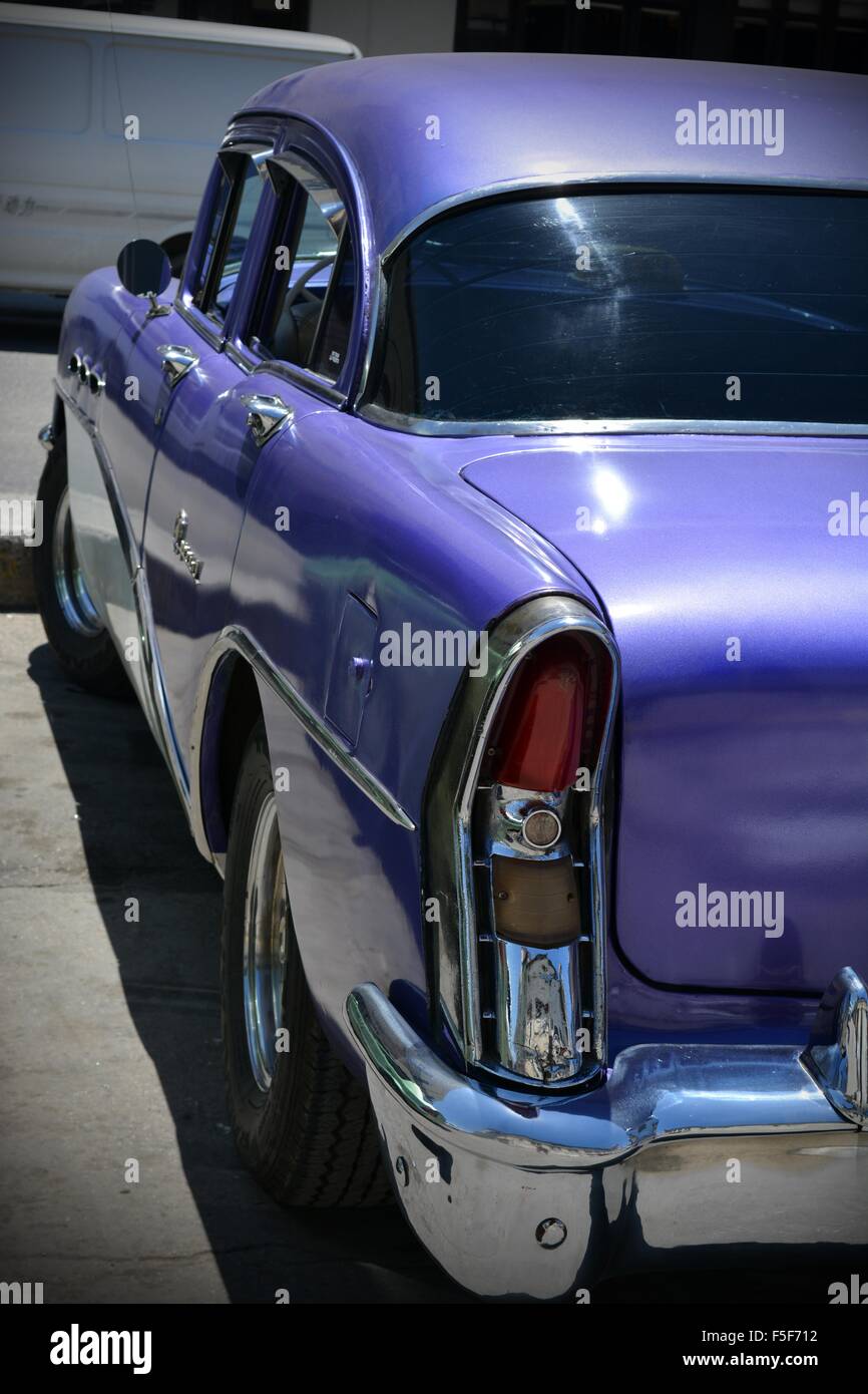 rear and side view of vintage purple Buick car parked on a quiet street ...