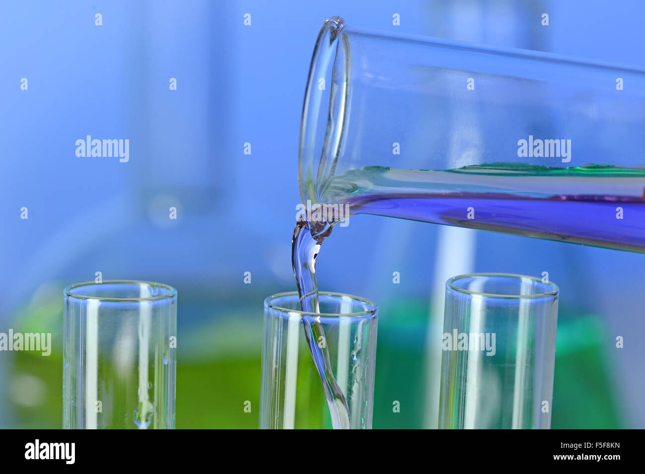Liquid being poured from beaker into test tube Stock Photo - Alamy