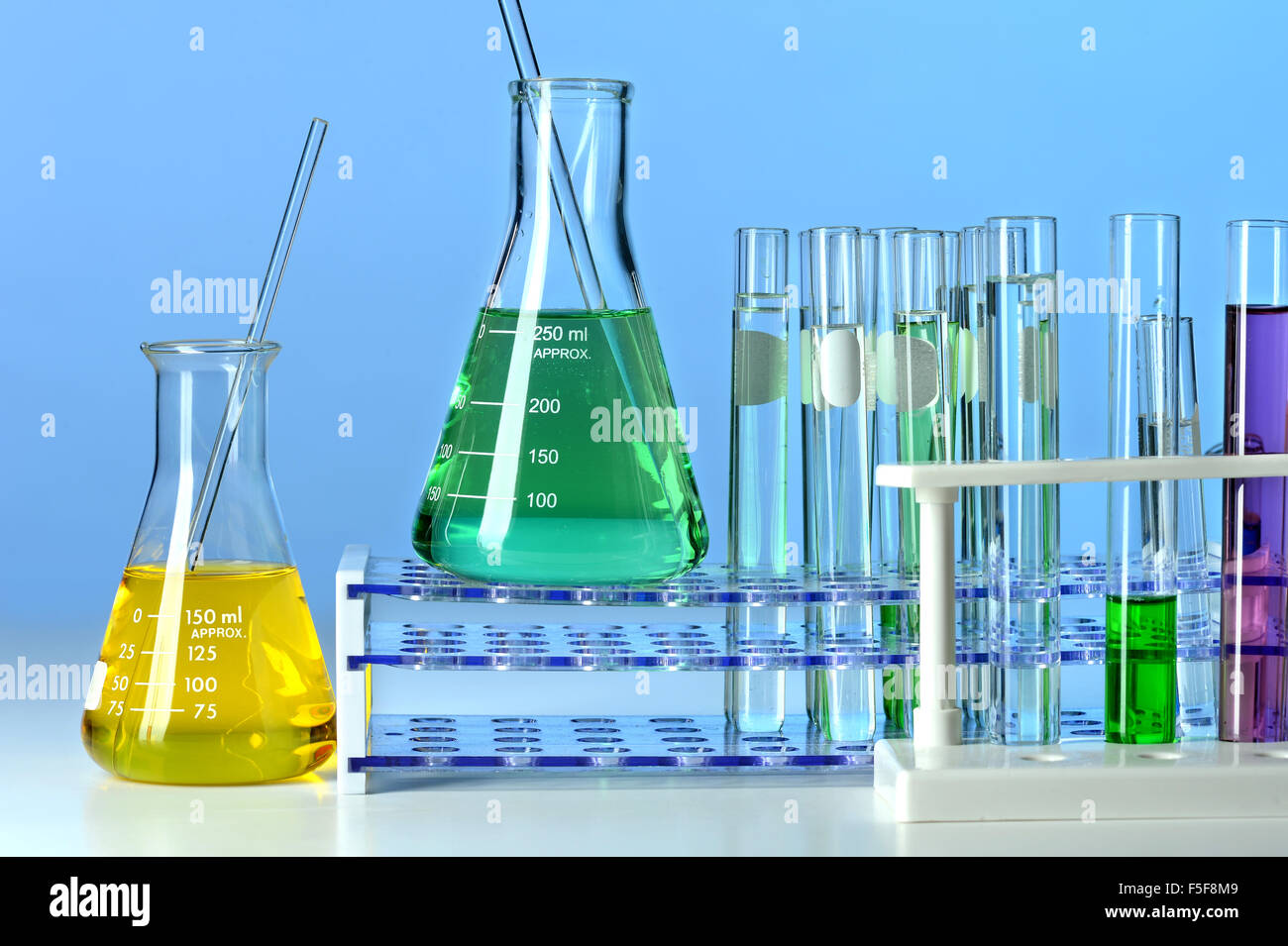Laboratory glassware over table and blue background Stock Photo - Alamy