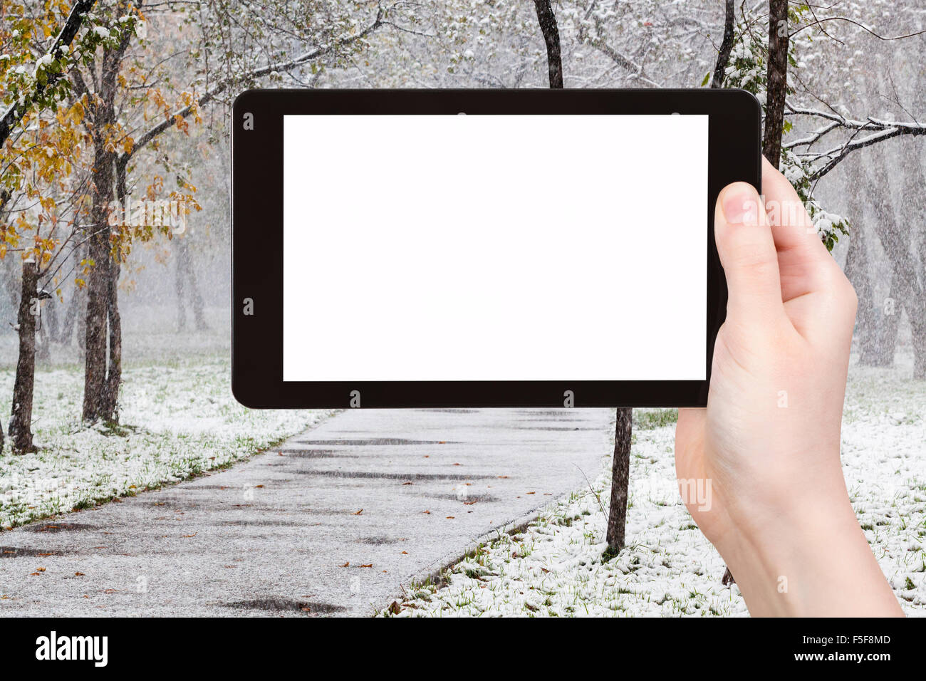 season concept - hand holds tablet pc with cut out screen and first ...