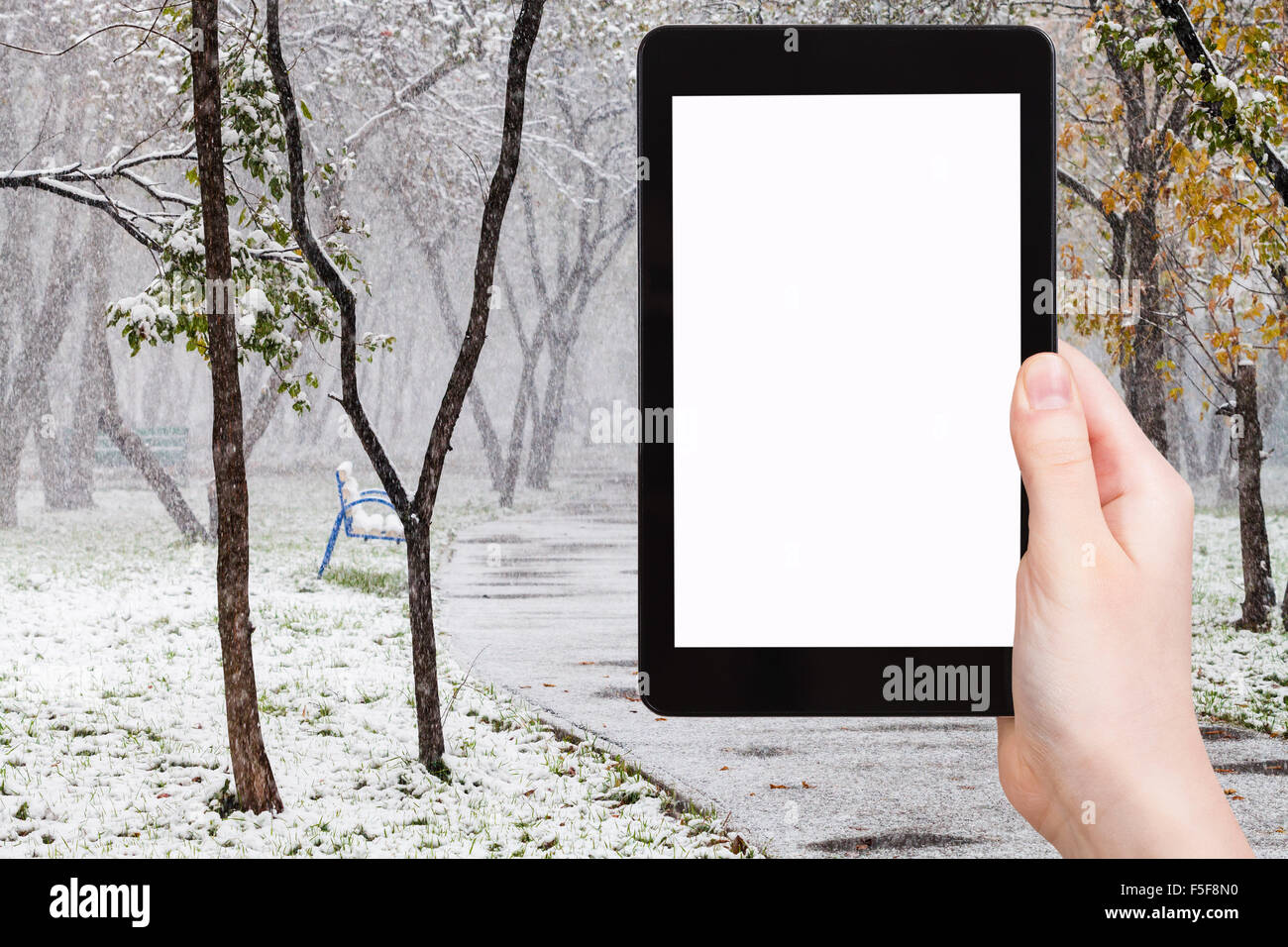 season concept - hand holds tablet pc with cut out screen and first ...