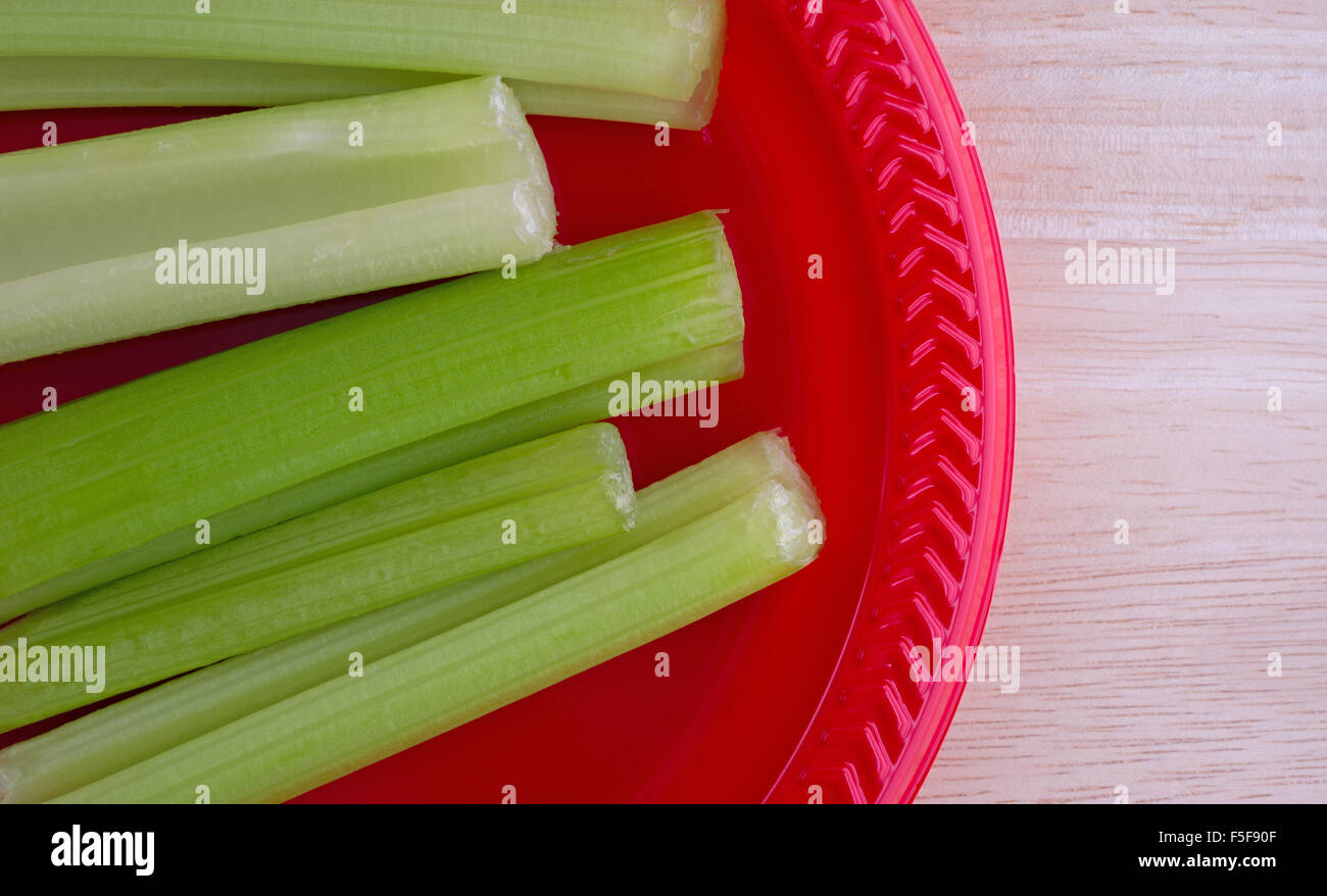 Top close view of a small serving of celery on a red plastic plate atop ...