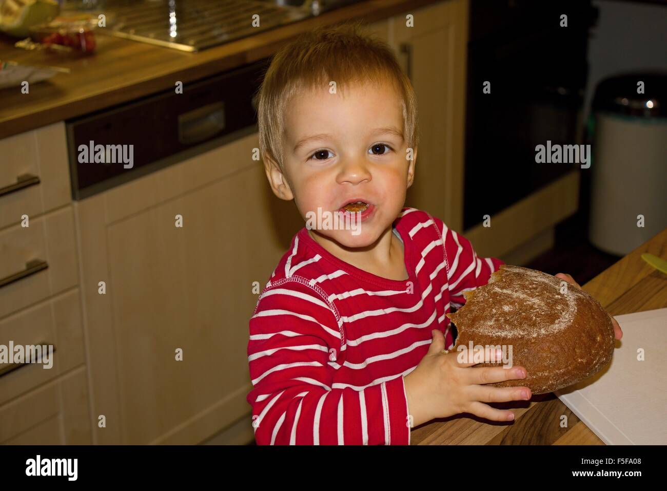 Little blonde boy eat fresh bread Stock Photo - Alamy