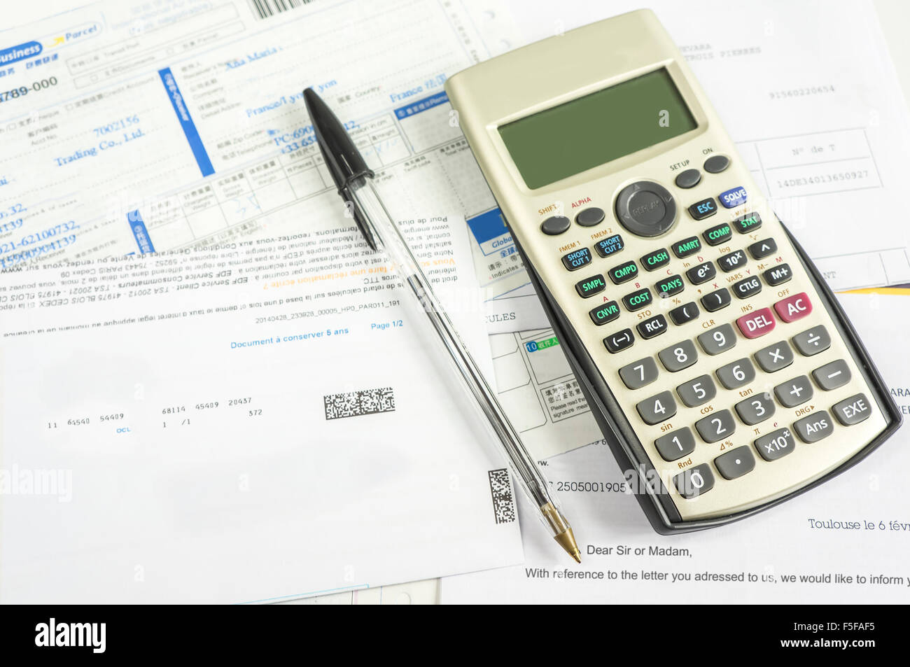 A calculator and pen over some random bills Stock Photo - Alamy