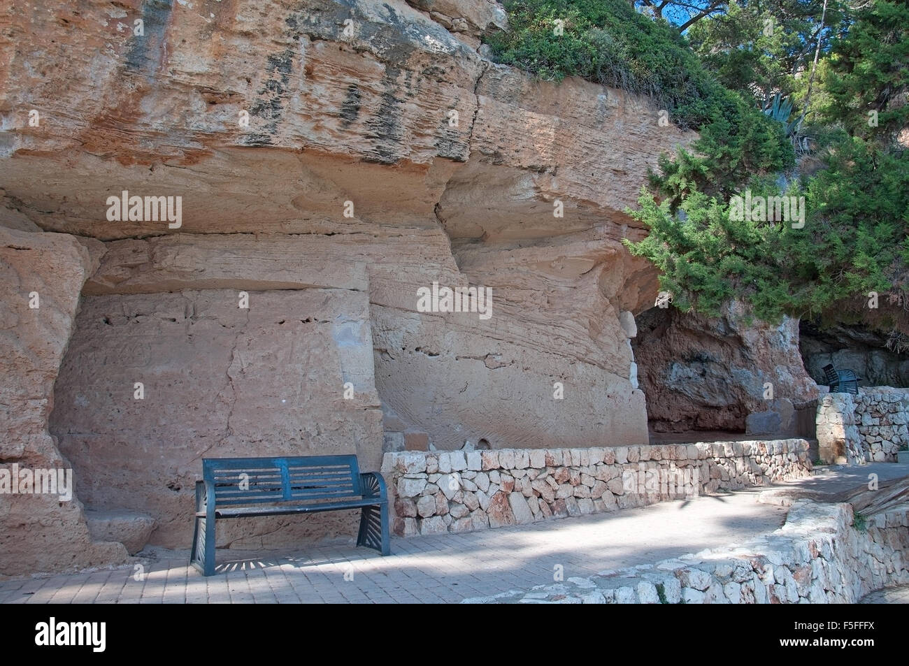 Bench under massive limestone rock formation with cracks and drystone ...