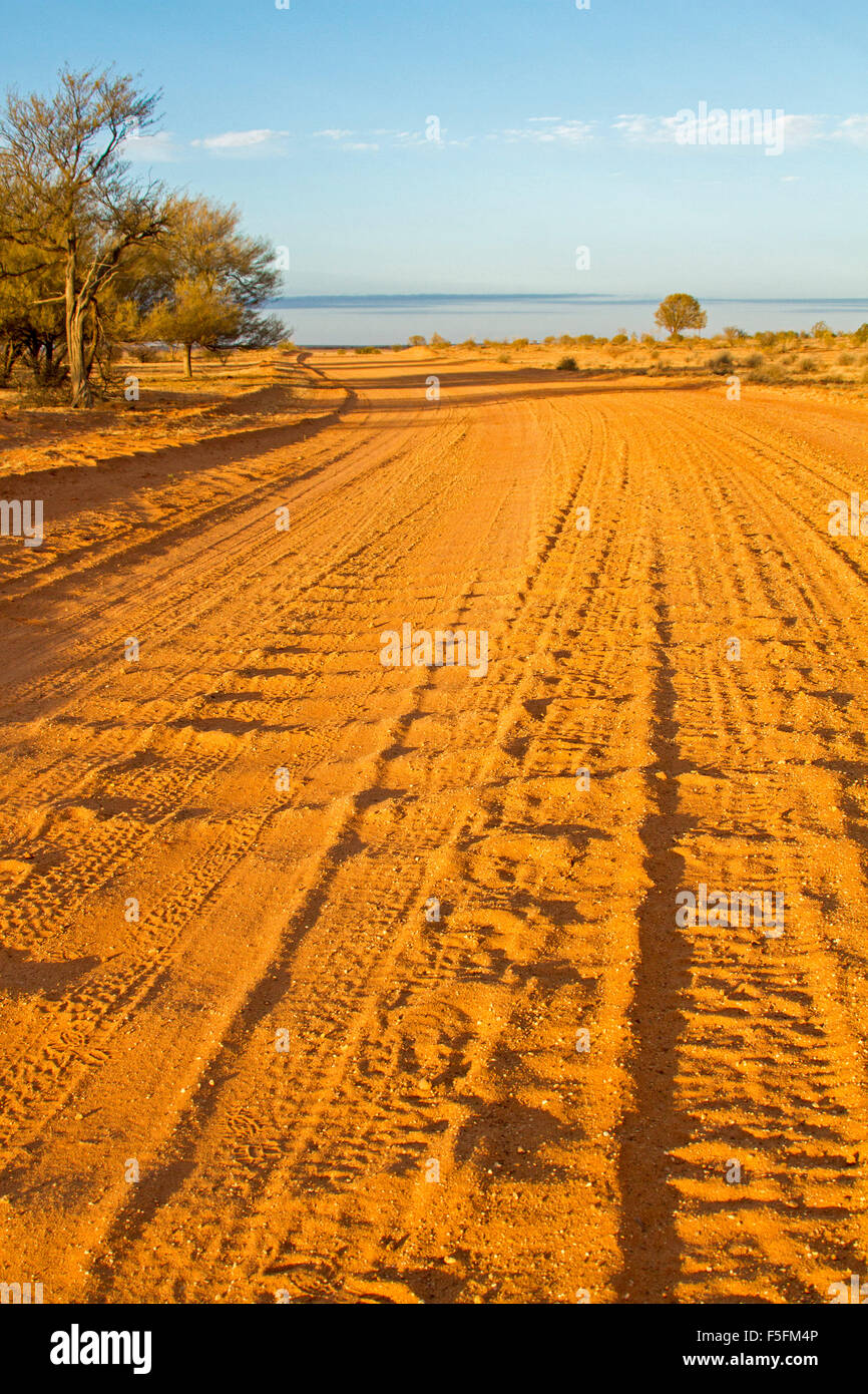 Rough and corrugated sandy red dirt road stretching to distant horizon ...