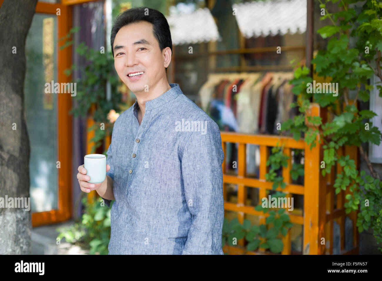 Male shopkeeper standing in doorway with a cup of tea Stock Photo - Alamy