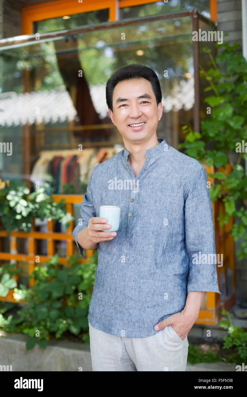 Male shopkeeper standing in doorway with a cup of tea Stock Photo - Alamy