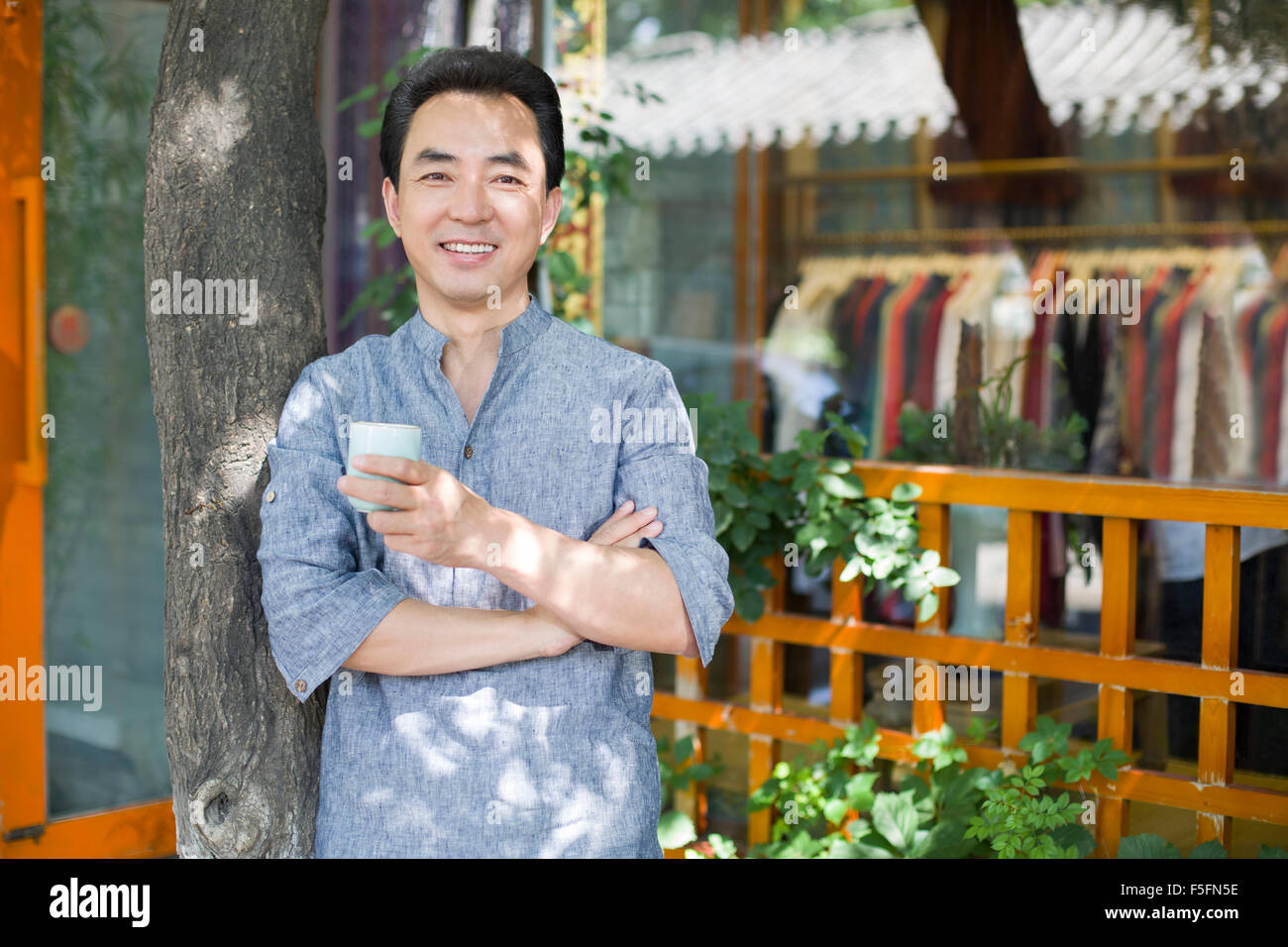 Male shopkeeper standing in doorway with a cup of tea Stock Photo - Alamy