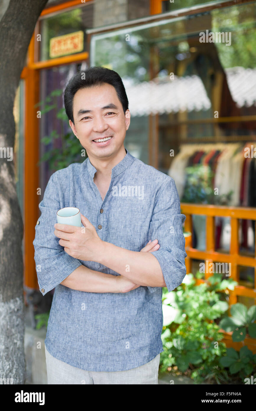 Male shopkeeper standing in doorway with a cup of tea Stock Photo - Alamy