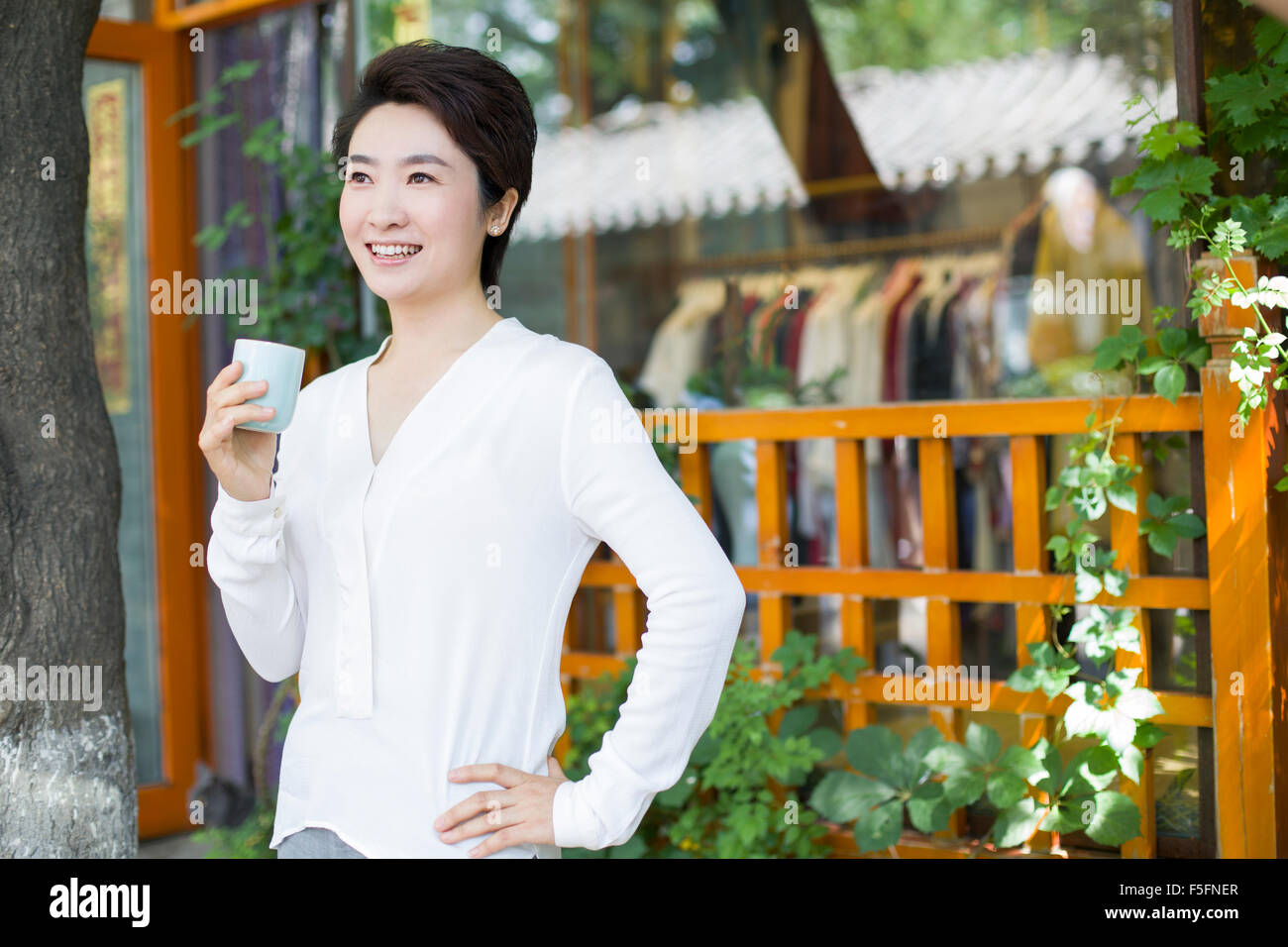 Female shopkeeper standing in doorway with a cup of tea Stock Photo - Alamy